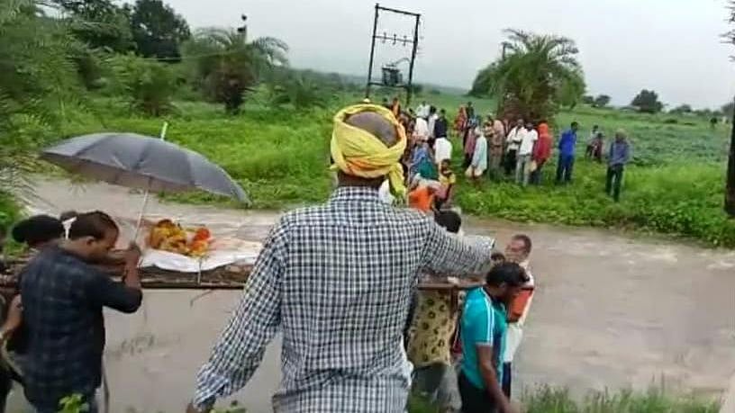 Mhow: Villagers forced to wade through a river to lay their dead to rest